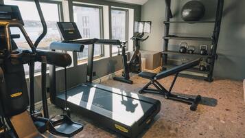Uma academia com máquinas de cardio, pesos e esteira.