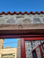 Um edifício de pedra com uma porta vermelha e guarda-corpo de varanda em metal.