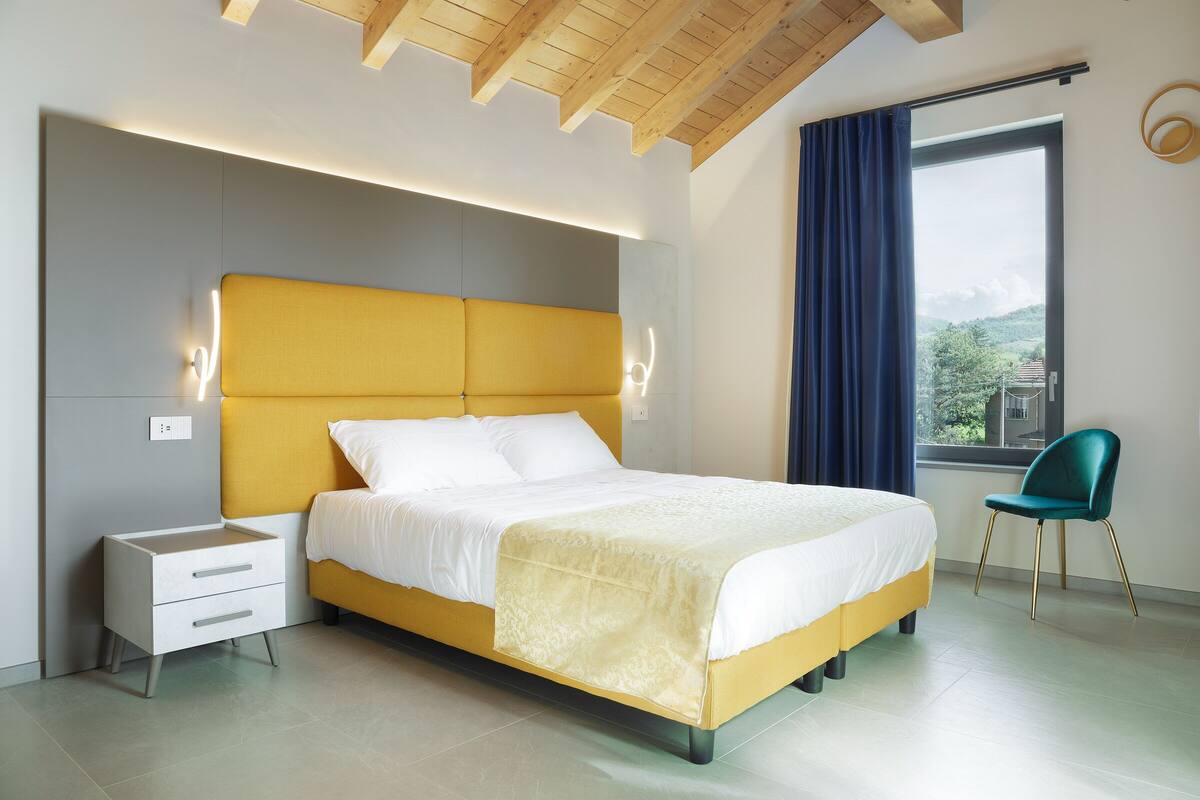 Quarto moderno com cama, mesa de cabeceira e uma cadeira.