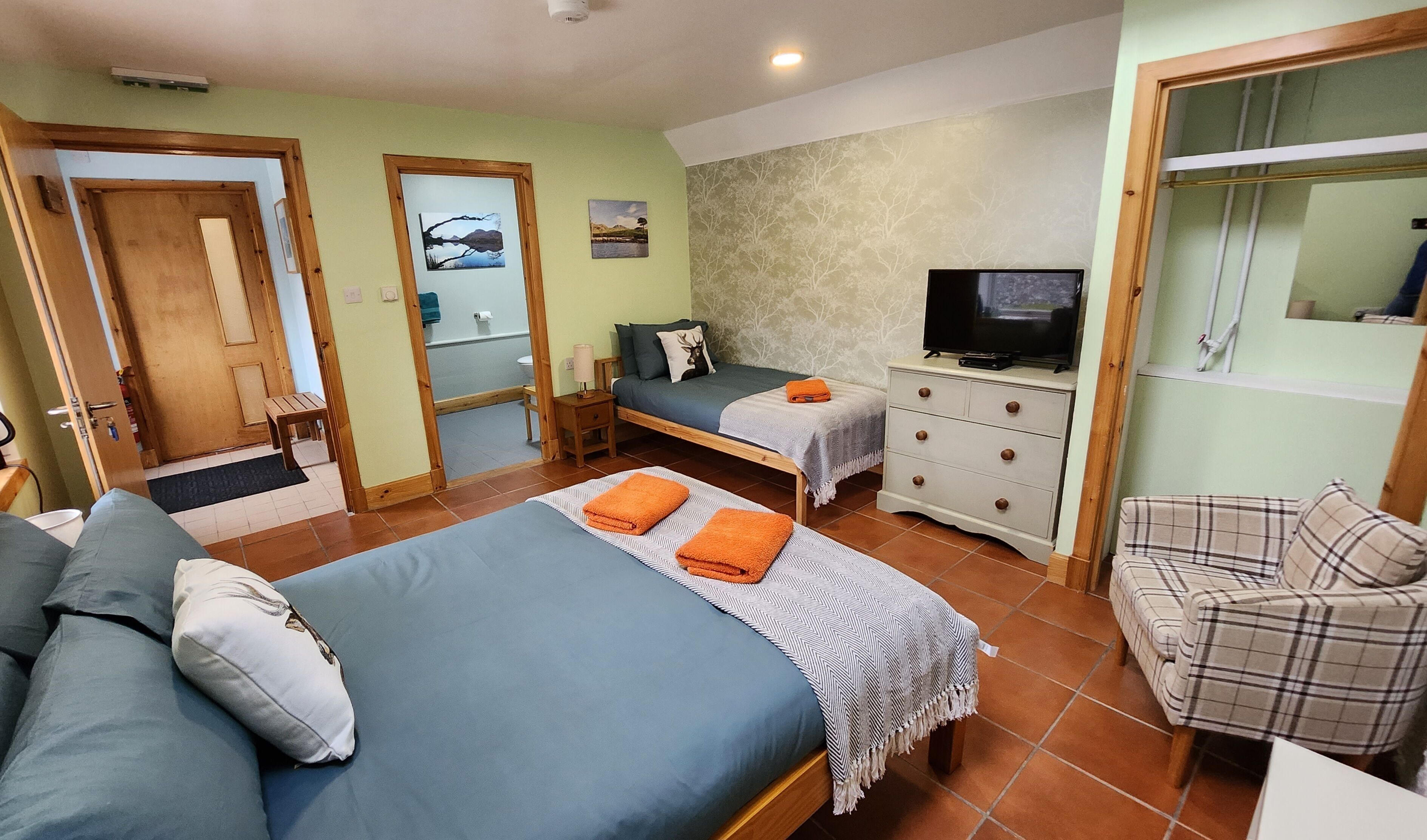 Quarto com cama, televisão, cômoda e cadeira.