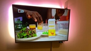Televisão de tela plana na parede exibindo uma cena de comida.