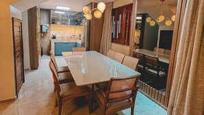 Uma sala de jantar moderna com uma mesa comprida, cadeiras de madeira e um lustre.