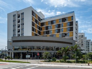Um edifício moderno com fachada de vidro, entrada visível e uma placa com a inscrição 'ELYMPIA CROSSFIT FITNESS'.
