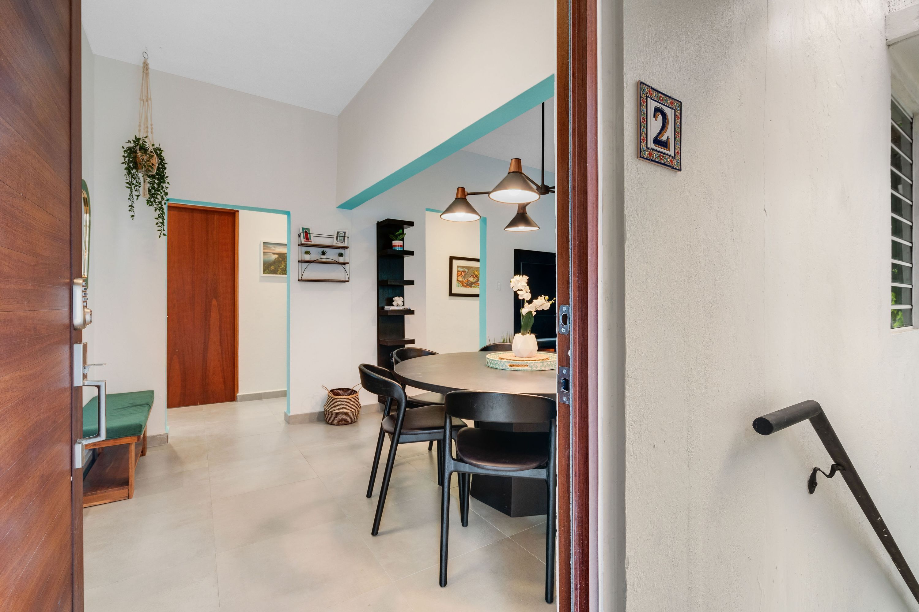 Uma área de refeições com mesa redonda, cadeiras pretas e iluminação pendente.
