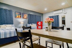 Quarto de hotel com duas camas, uma mesa de jantar, cadeiras, um vaso com flores e um aviso indicando zona com Wi-Fi gratuito.