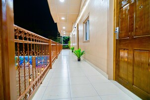Um corredor com piso de azulejos, portas de madeira e corrimão com luzes de cordão.