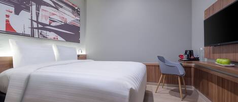 Quarto de hotel moderno com uma cama grande, uma escrivaninha com cadeira, uma TV de tela plana e um grande quadro abstrato na parede.