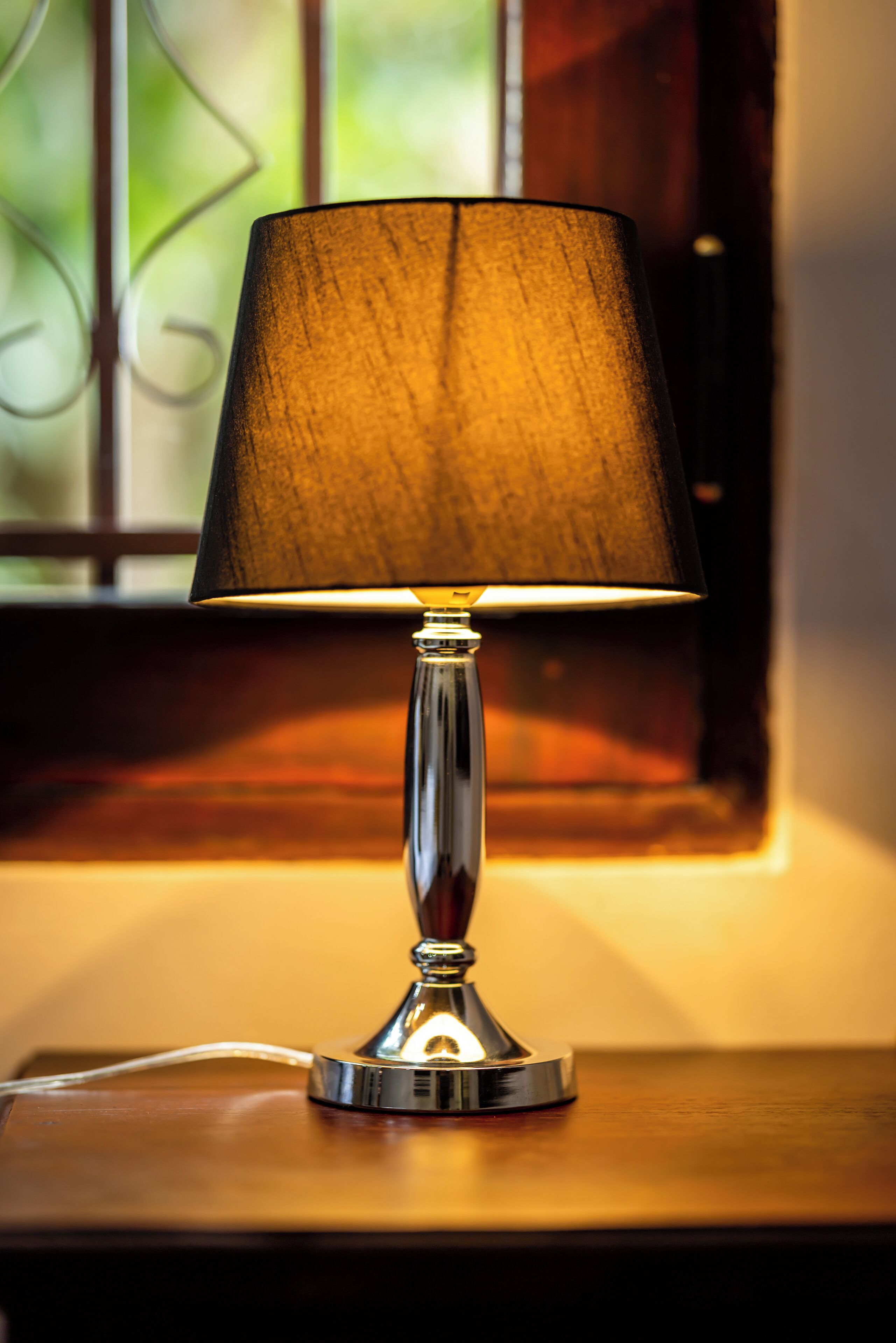 Uma luminária de mesa com cúpula preta sobre uma superfície de madeira.