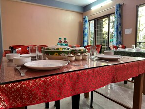 Uma sala de jantar com uma mesa posta para quatro pessoas, incluindo pratos, tigelas e xícaras.