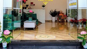 Uma área de recepção com o letreiro 'YORI HOUSE', um balcão de atendimento e plantas em vasos.