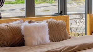 Cama com vista para uma área residencial através de grandes janelas.