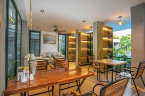 Sala de estar moderna com mesa de jantar de madeira, assentos confortáveis e vista para o verde lá fora.