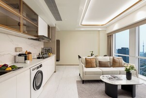 Uma sala de estar moderna com sofá, mesa de centro e vista para a cidade através de janelas amplas.