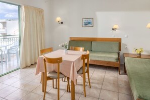 Uma sala de jantar com mesa posta para quatro pessoas, um sofá e uma varanda com cadeiras.