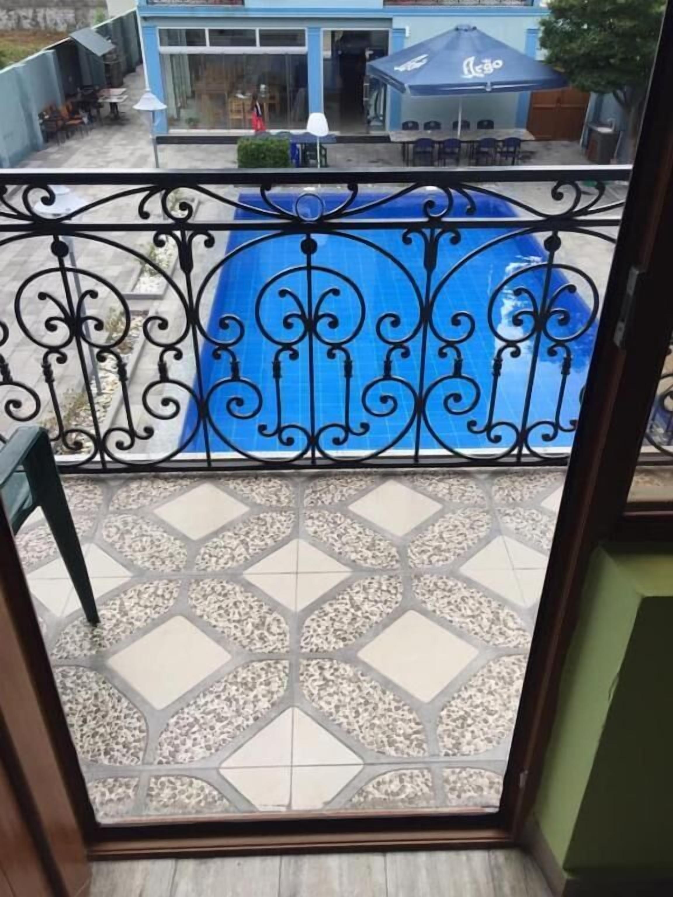 Uma varanda com vista para uma piscina azul e um edifício com área de estar externa.
