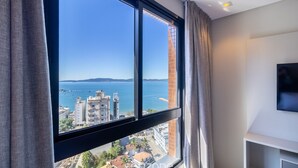 Quarto com uma janela grande, televisão de tela plana e prateleira branca.