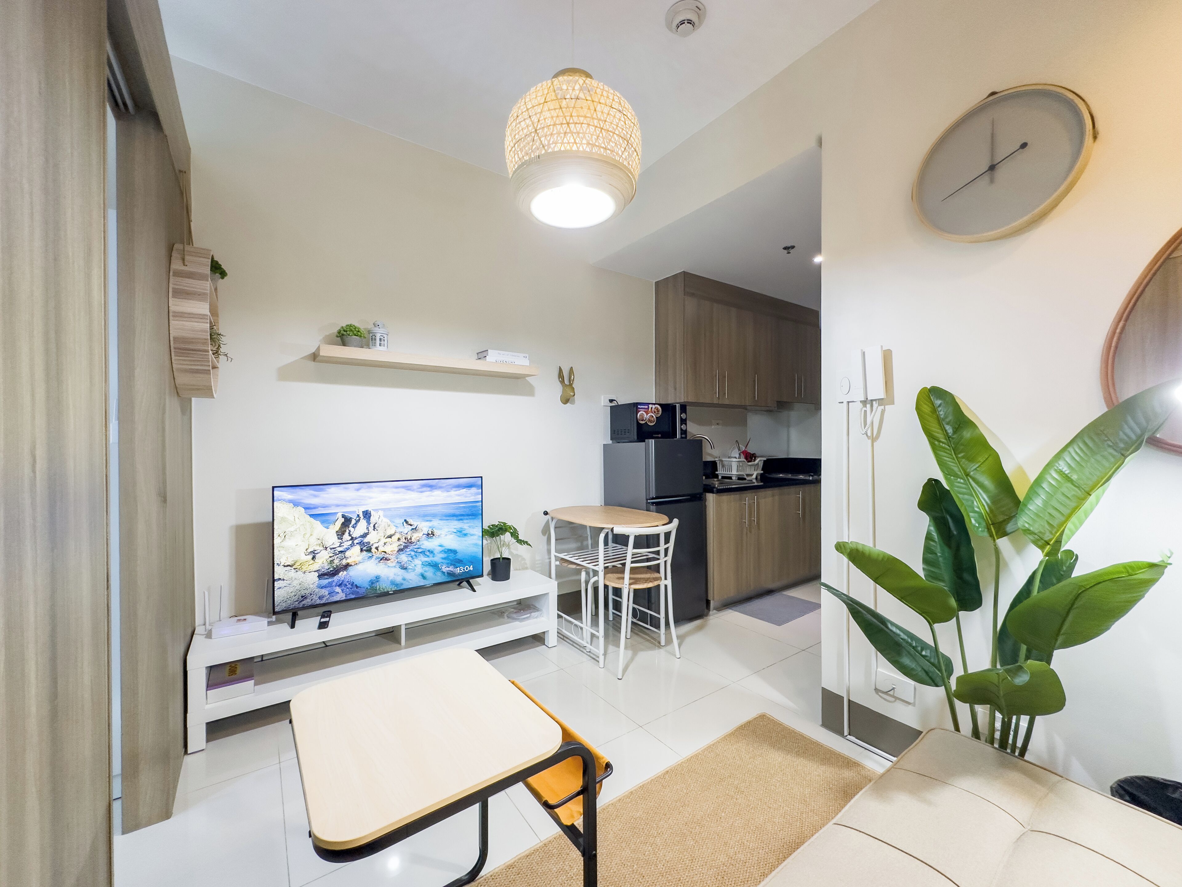 Um apartamento moderno com televisão, sala de jantar, cozinha e uma planta grande.