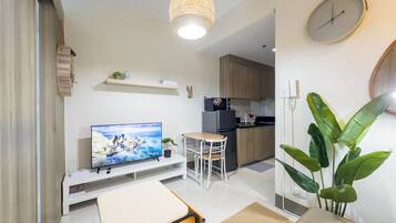 Um apartamento moderno com televisão, sala de jantar, cozinha e uma planta grande.
