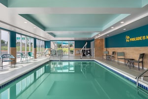 Área de piscina com paredes de vidro transparente, esquema de cores azul e branco e uma placa com a inscrição 'POOLSIDE IS'.