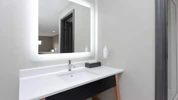 Casa de banho moderna com lavatório branco, toucador preto e um espelho grande.
