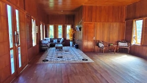 Um quarto espaçoso com piso de madeira, um sofá, cadeiras e um tapete estampado.