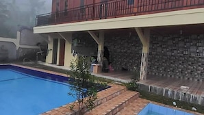Um edifício de dois andares com varanda, piscina e muro de pedra.