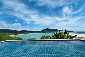 Piscina com vista para uma praia e montanhas.