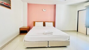 Quarto com cama, mesa de cabeceira e relógio na parede.