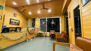 Um quarto acolhedor com piso de madeira, balcão de recepção, área de estar e uma grande janela.