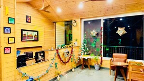 Uma área de recepção acolhedora, decorada com madeira, um relógio e uma janela com enfeites festivos.