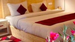 Uma cama de madeira com roupa de cama branca e almofadas vermelhas em um quarto com teto de madeira.