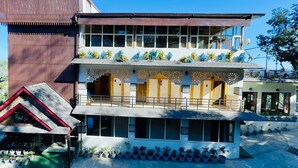 Um edifício de dois andares com varanda, plantas em vasos e uma placa com a inscrição 