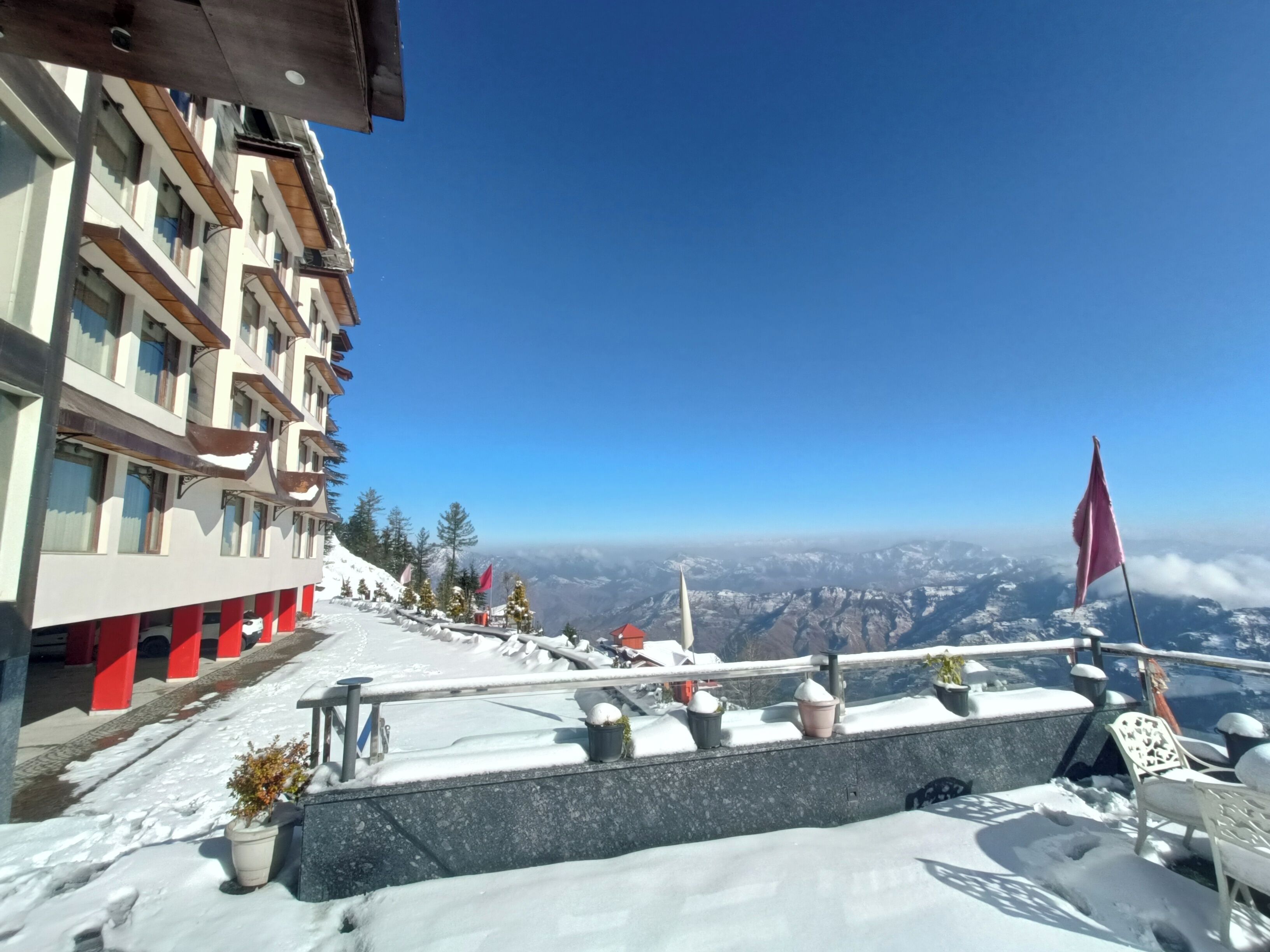 Um hotel com vista para montanhas cobertas de neve e um céu azul límpido.