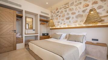Quarto com cama grande, guarda-roupa de madeira, estantes embutidas, parede de pedra e luminária pendente.