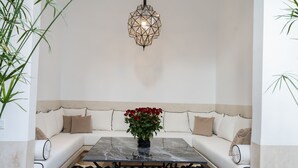 Uma sala de estar moderna com um sofá seccional, uma mesa de centro de mármore e um lustre geométrico.