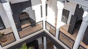 Pátio com vários níveis, uma escadaria central, paredes brancas e guarda-corpos pretos.