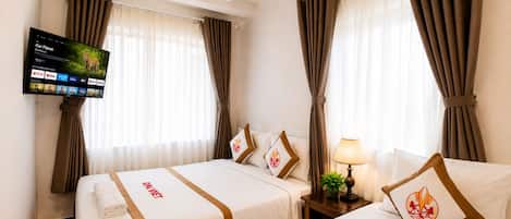 Quarto de hotel com duas camas, uma TV fixada na parede e cortinas nas janelas.