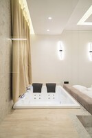 Um banheiro moderno com uma banheira independente, piso de madeira, cortinas bege e arandelas de parede minimalistas.