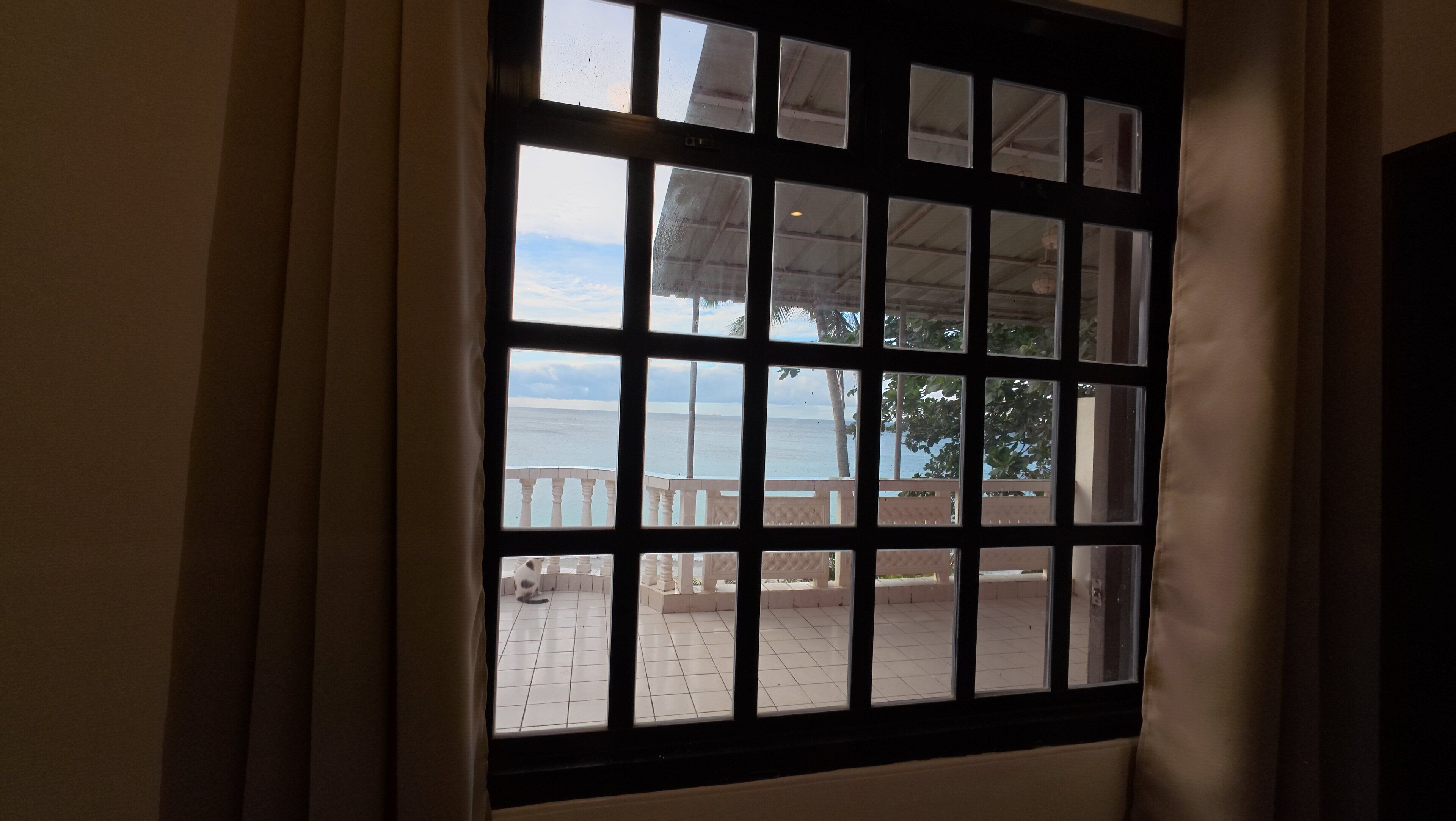Janela com vista para uma praia e um edifício com chão de azulejos.