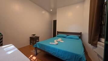 Quarto com cama, mesa de cabeceira pequena, planta em vaso e janela com cortinas.