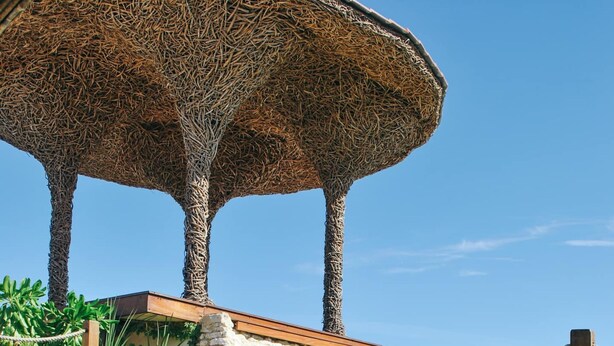 Uma área de piscina com uma barreira de corda, um deck de madeira e um muro de pedra.