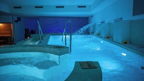 Piscina interna com tonalidade azul, várias entradas e um recurso aquático.