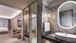 Quarto de hotel moderno com cama, escrivaninha e banheiro.