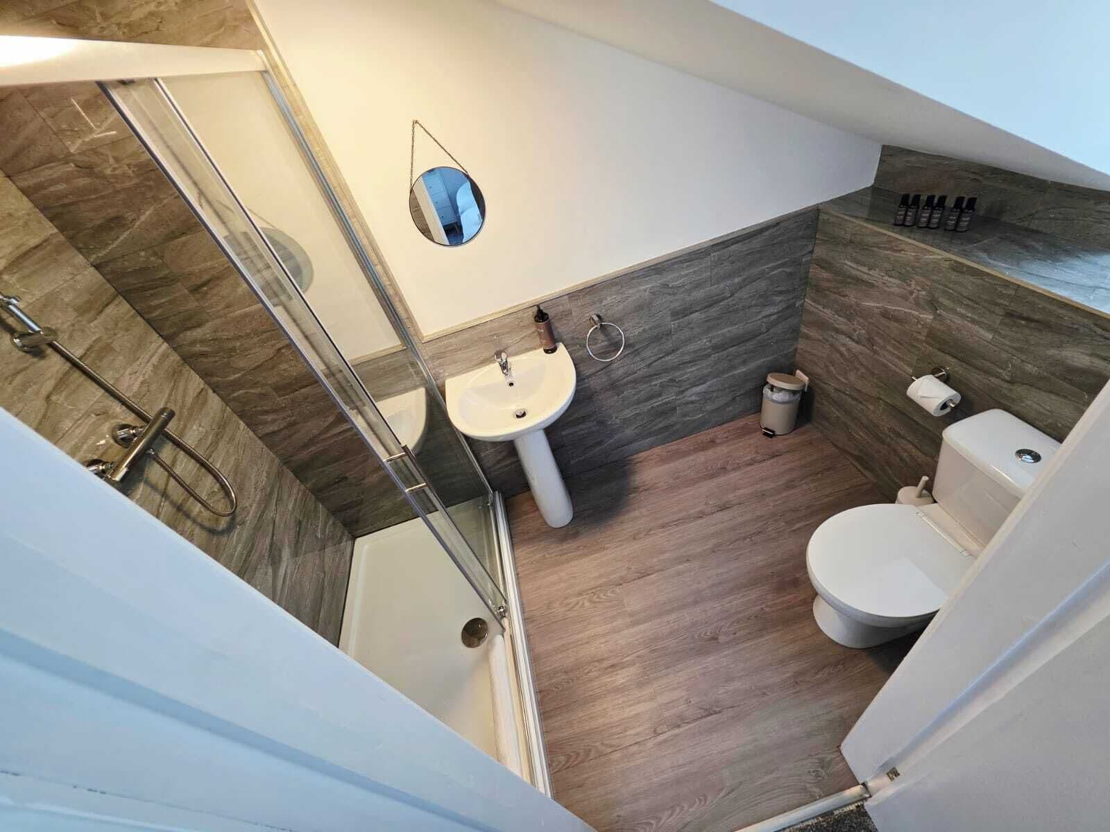 Uma casa de banho moderna com cabine de duche em vidro, lavatório suspenso e sanita.