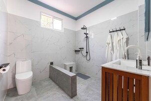 Uma casa de banho moderna com sanita, chuveiro e lavatório.