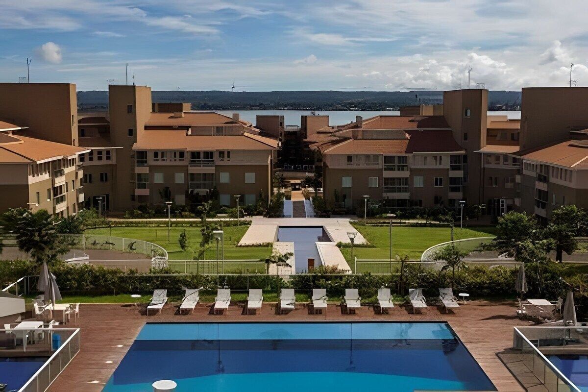 Um hotel com piscina, espreguiçadeiras e vista para os edifícios e paisagem ao redor.