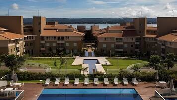 Um hotel com piscina, espreguiçadeiras e vista para os edifícios e paisagem ao redor.