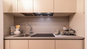Cozinha moderna com fogão embutido, pia e bancada com diversos utensílios de cozinha.