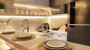 Uma cozinha moderna com micro-ondas integrado, eletrodomésticos de aço inoxidável e bancada de mármore.