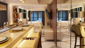 Quarto de hotel moderno com área de refeições, cama e televisão.